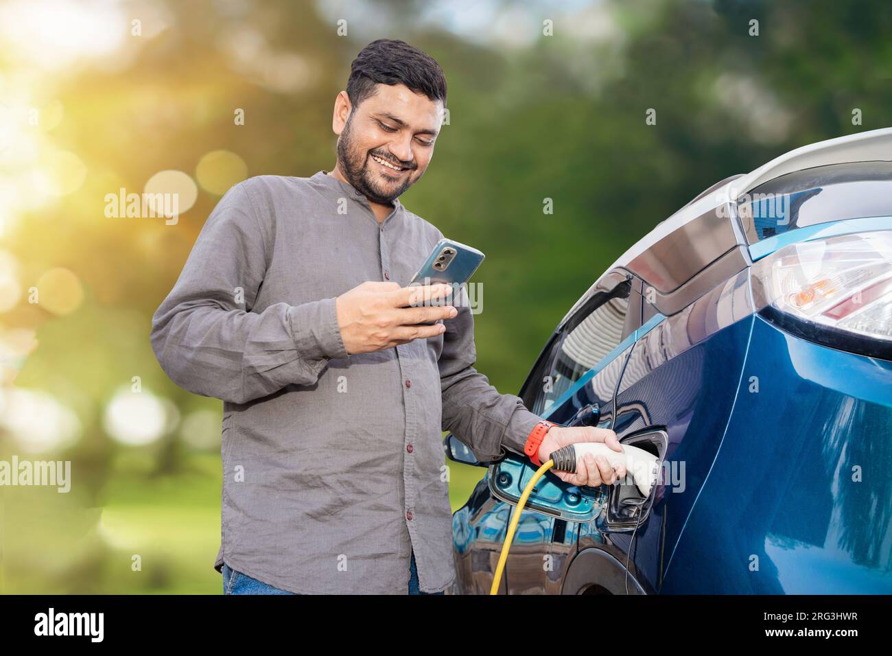 Happy Indian man attaching power cable into socket to charge his modern ...