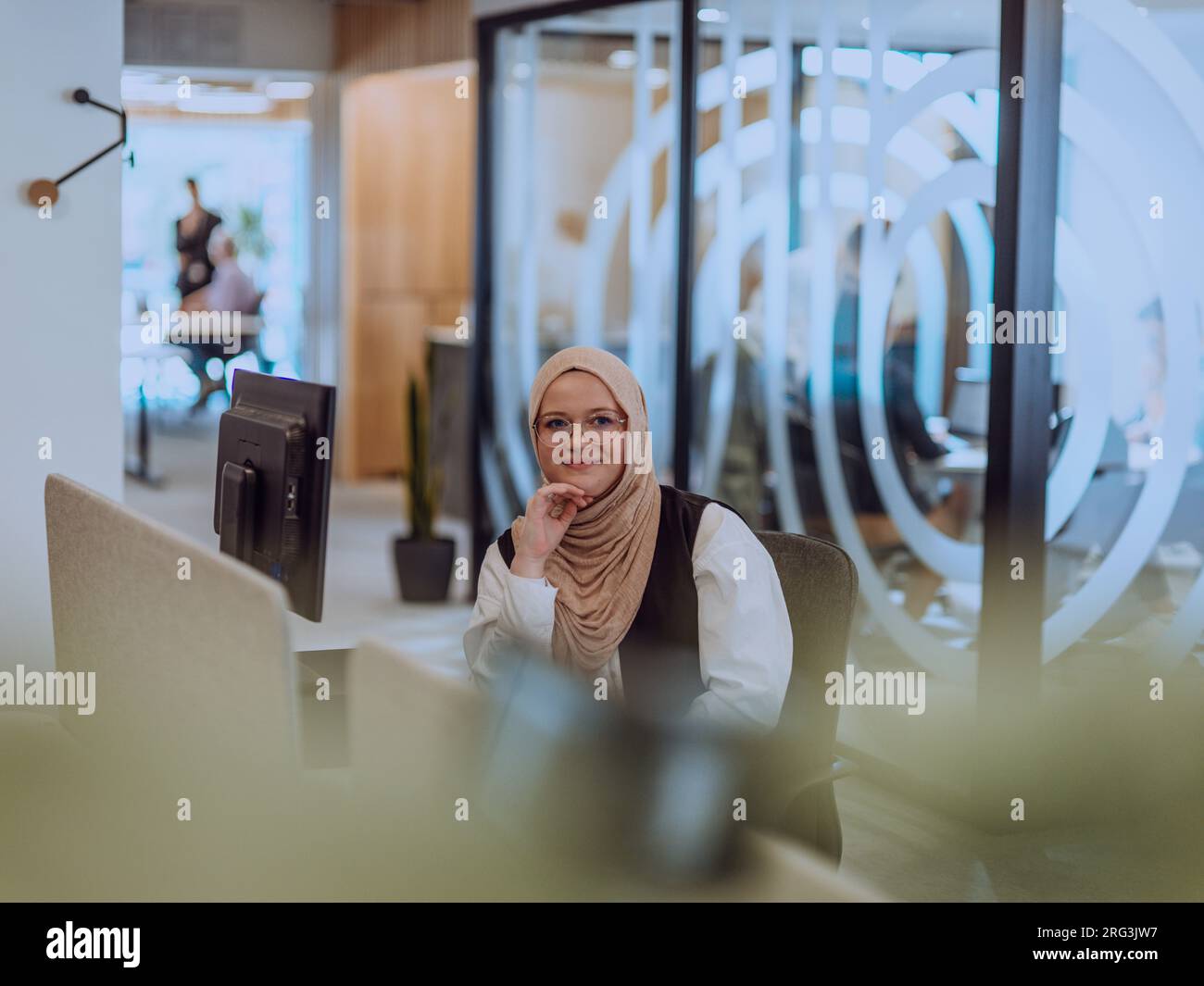 In a modern office, a young Muslim entrepreneur wearing a hijab sits ...