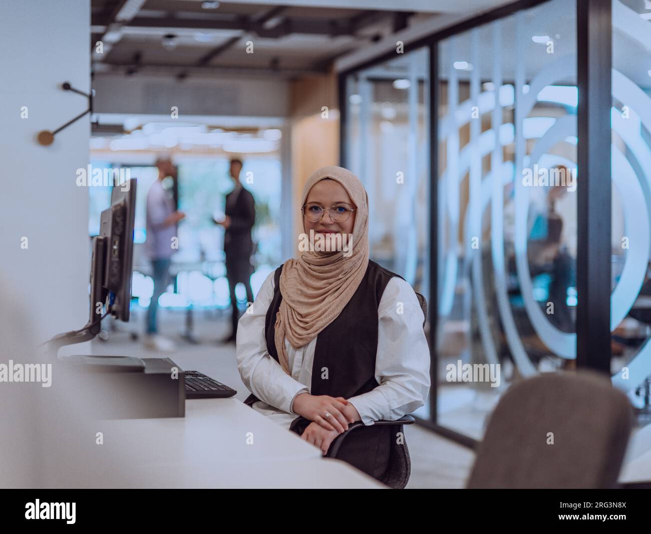 In a modern office, a young Muslim entrepreneur wearing a hijab sits ...