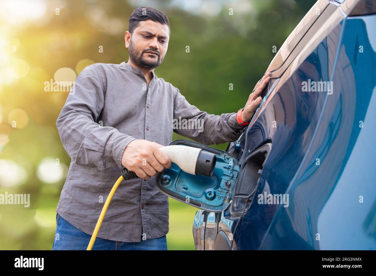 Indian man attaching power cable into socket to charge his modern ...