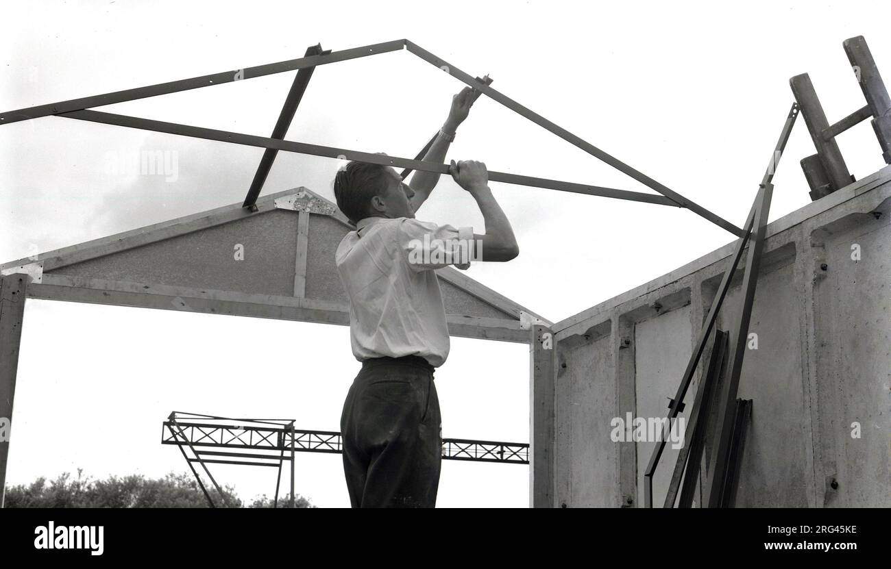 1950s, historical, a man installing a steel structure of a roof on a ...