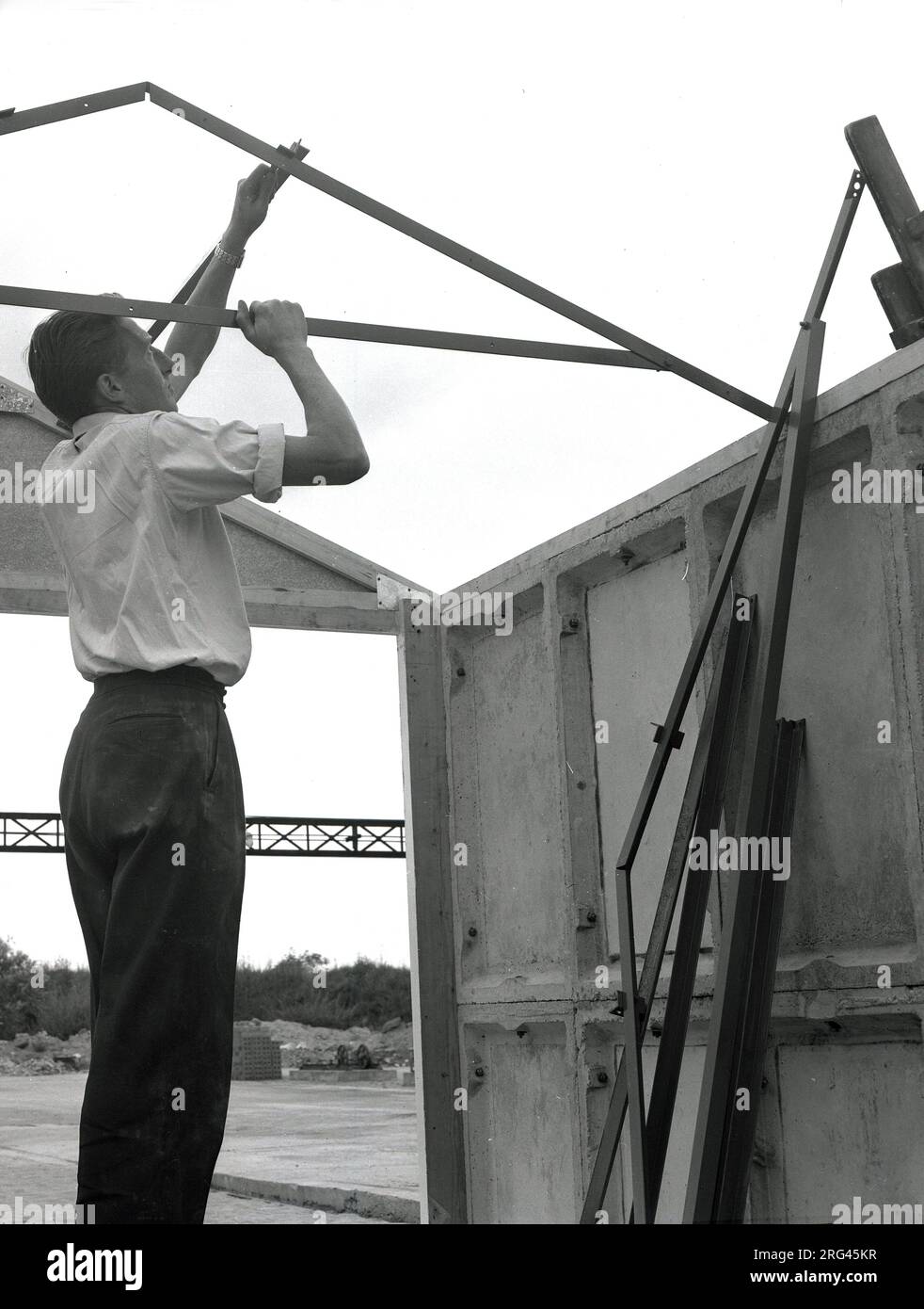 1950s, historical, a man installing a steel structure of a roof on a ...