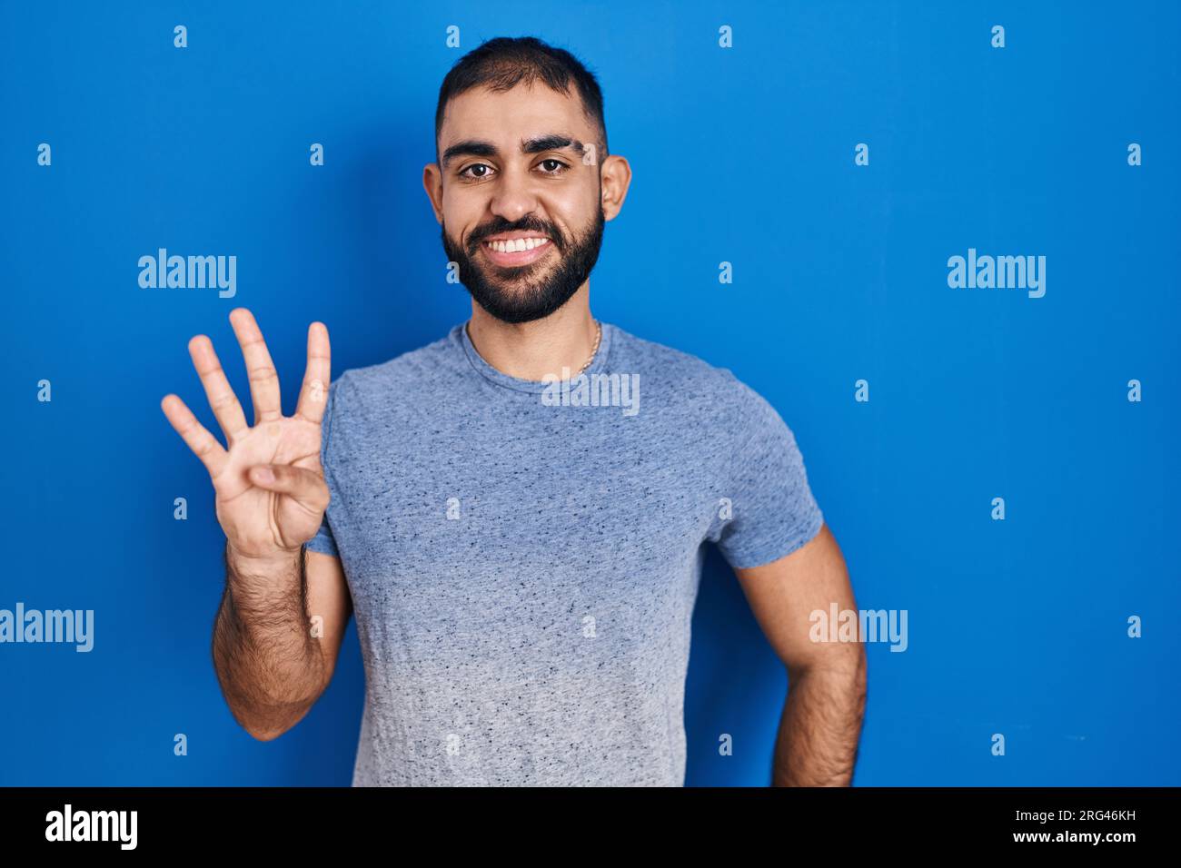 Middle east man with beard standing over blue background showing and ...