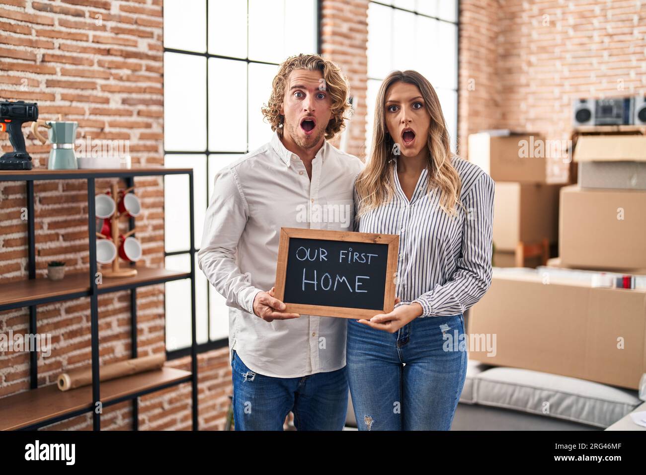 Young couple moving to a new home in shock face, looking skeptical and ...