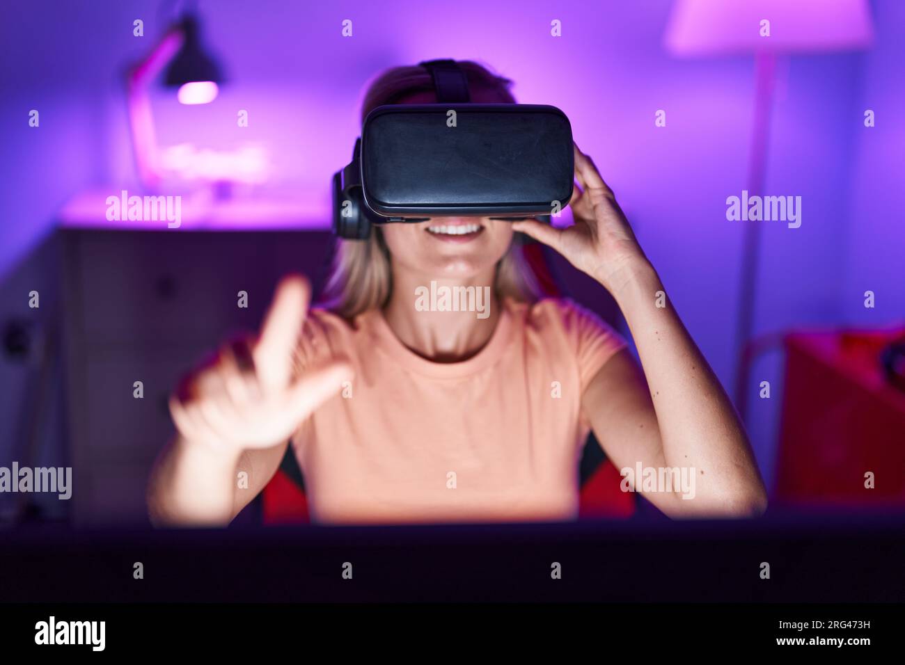 Young blonde woman streamer playing video game using virtual reality ...