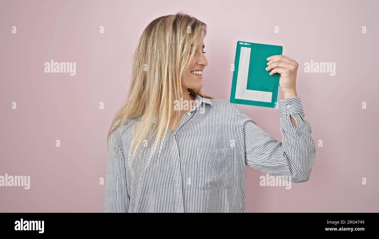 Young blonde woman smiling confident holding new driver license over ...