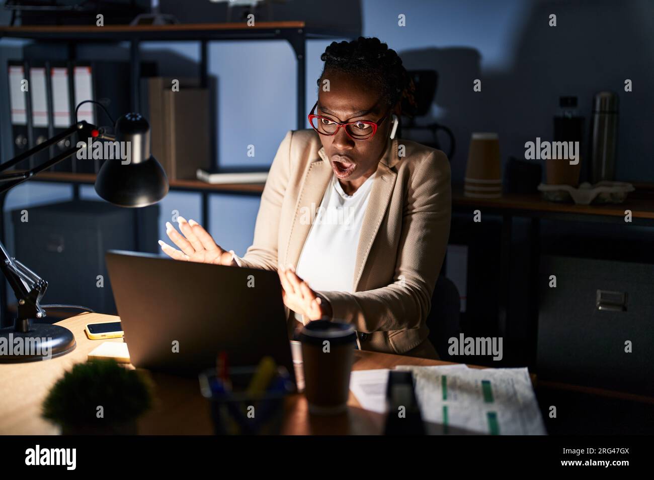 Beautiful black woman working at the office at night afraid and ...