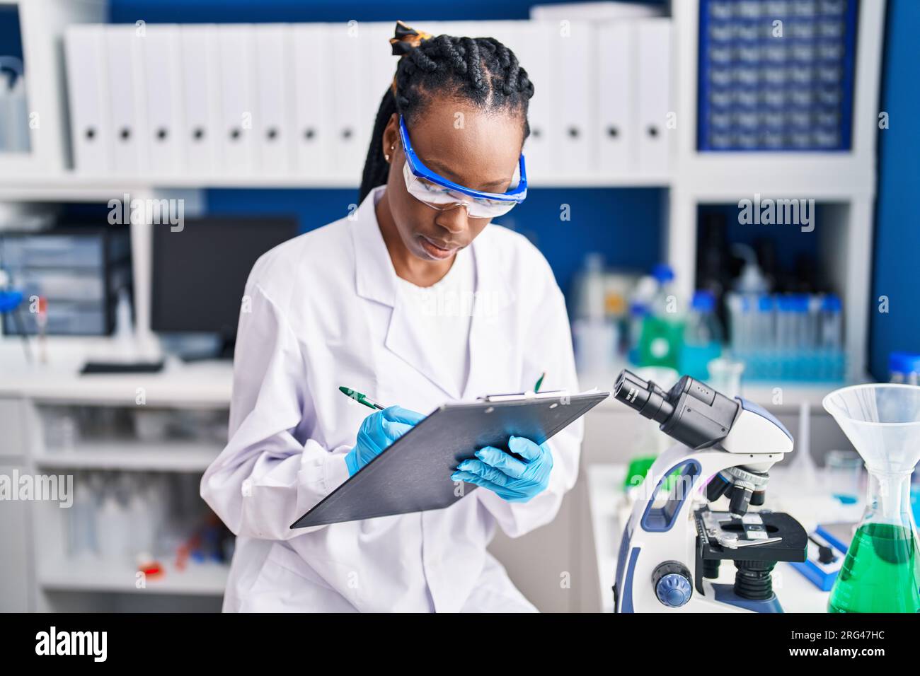 African american woman scientist writing on document at laboratory Stock Photo - Alamy