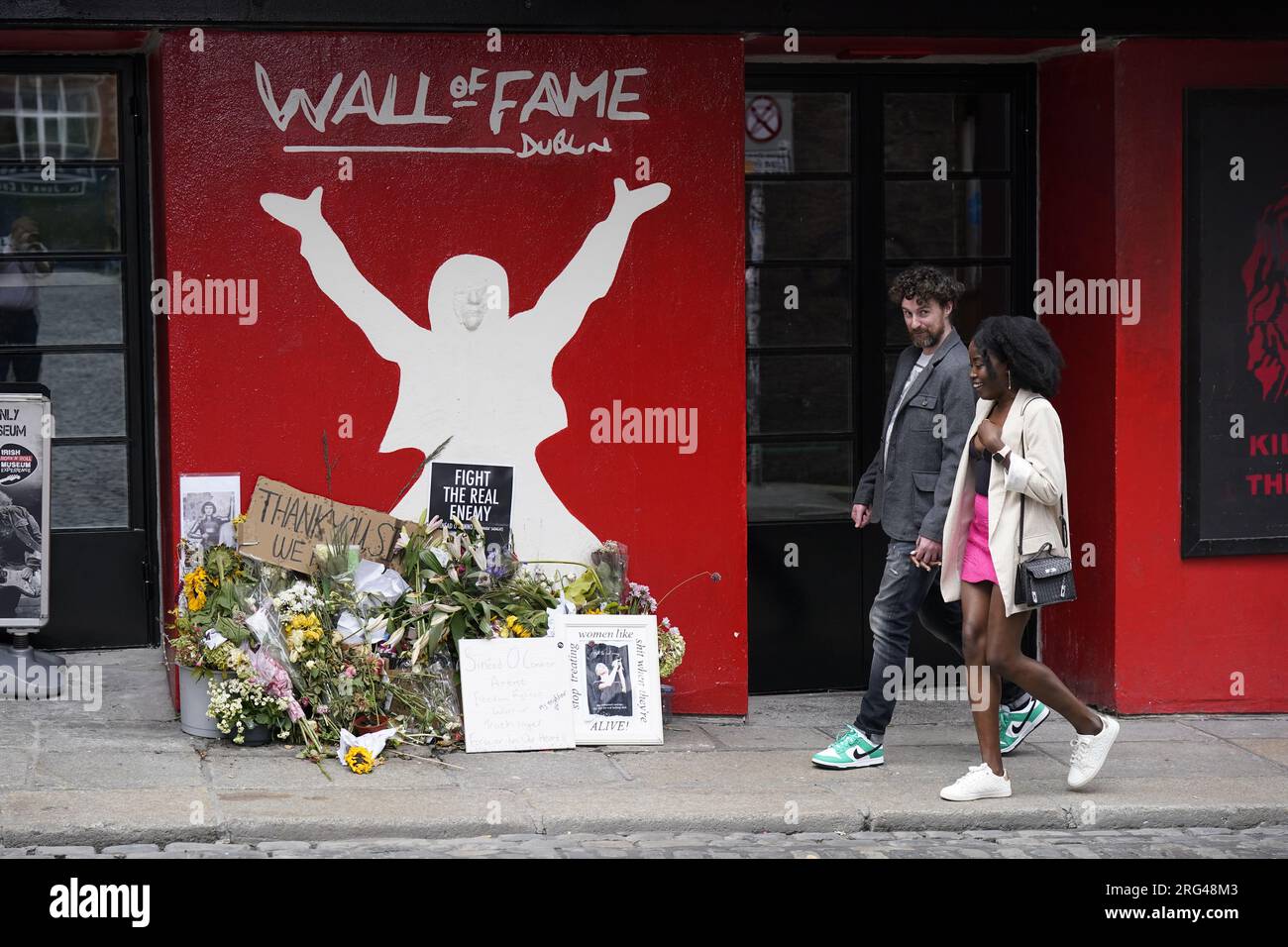 People walking past floral tributes to Sinead O'Connor at the music ...