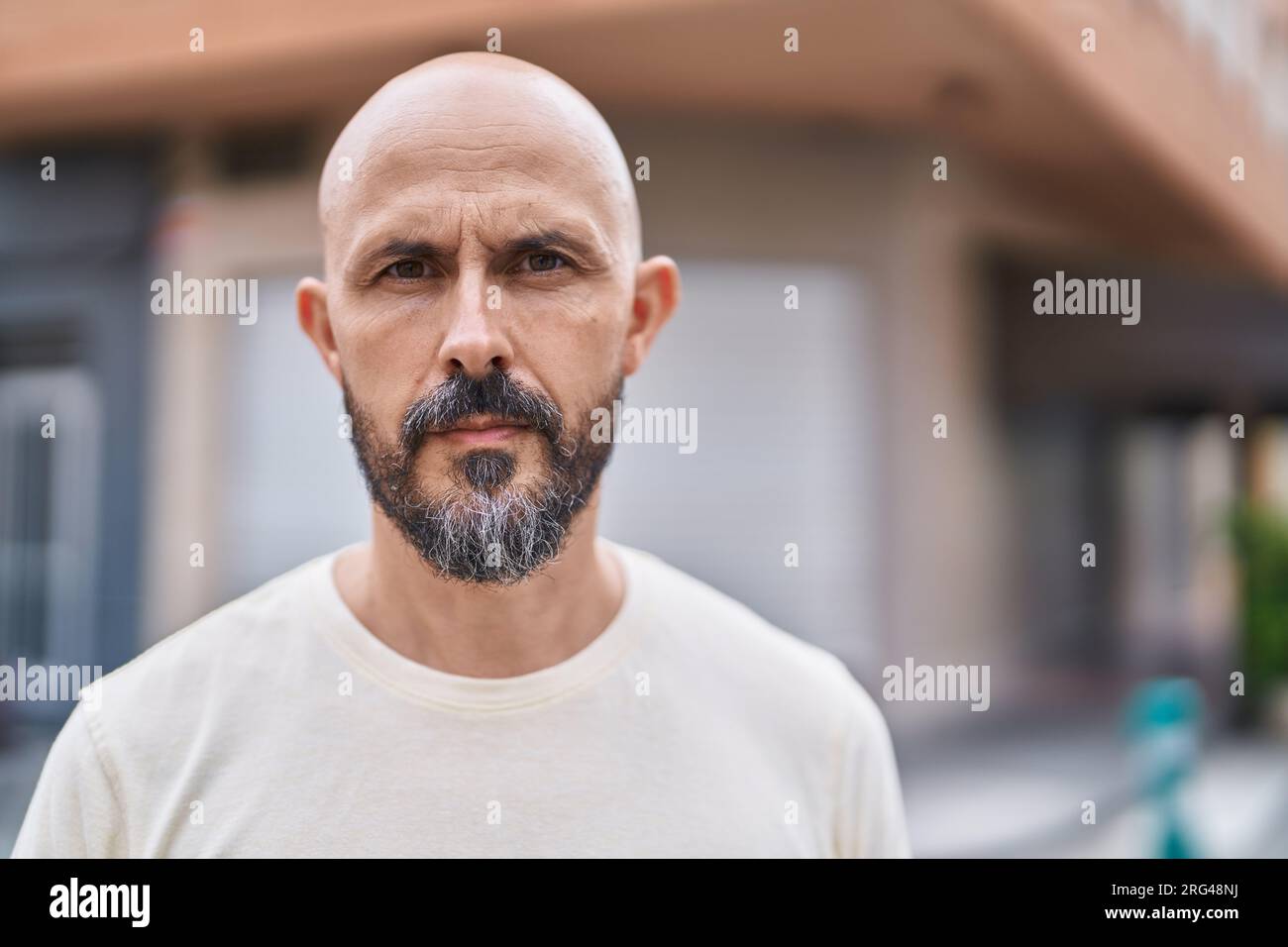 Young bald man standing with serious expression at street Stock Photo ...