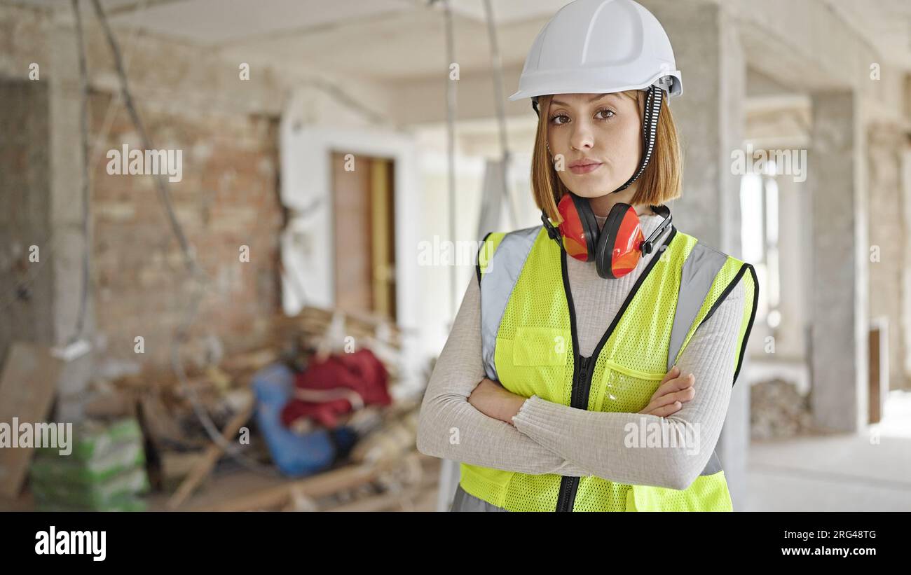 Young blonde woman architect standing with relaxed expression and arms ...