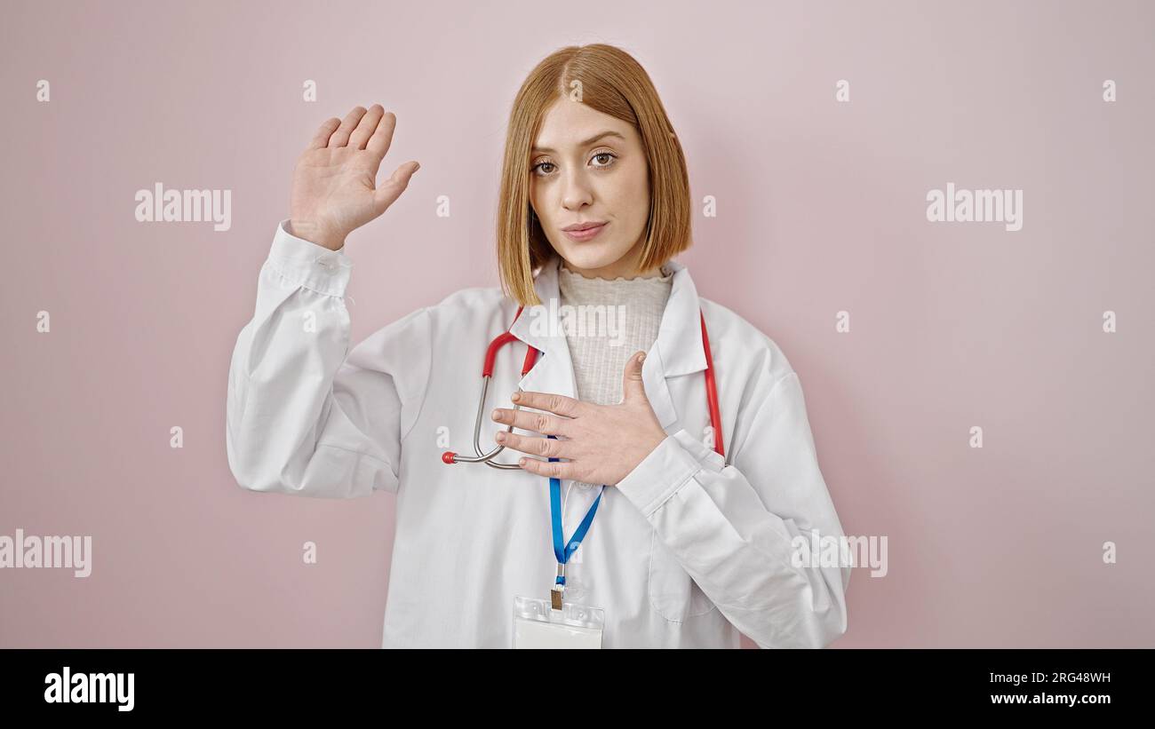 Young blonde woman doctor making an oath with hand on chest over ...