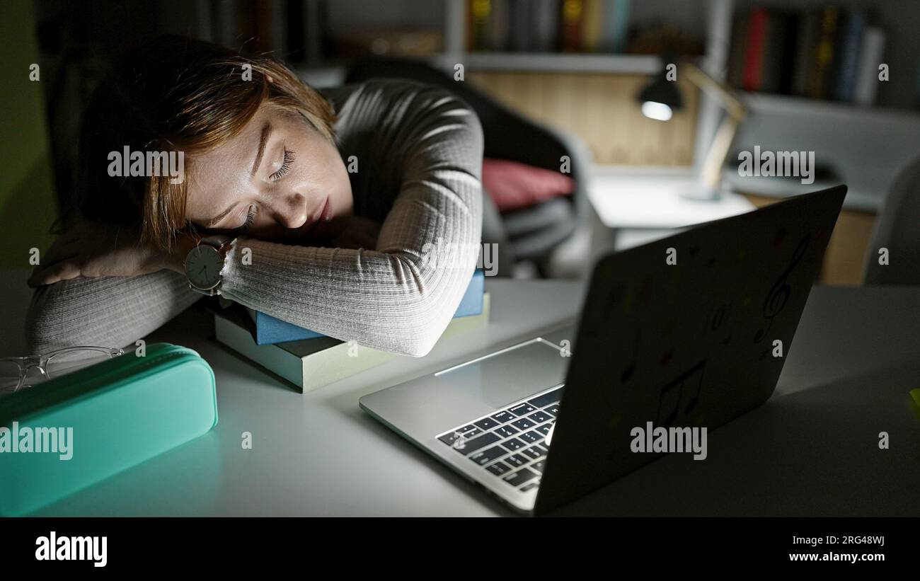 Young blonde woman student sleeping on the desk at library university ...