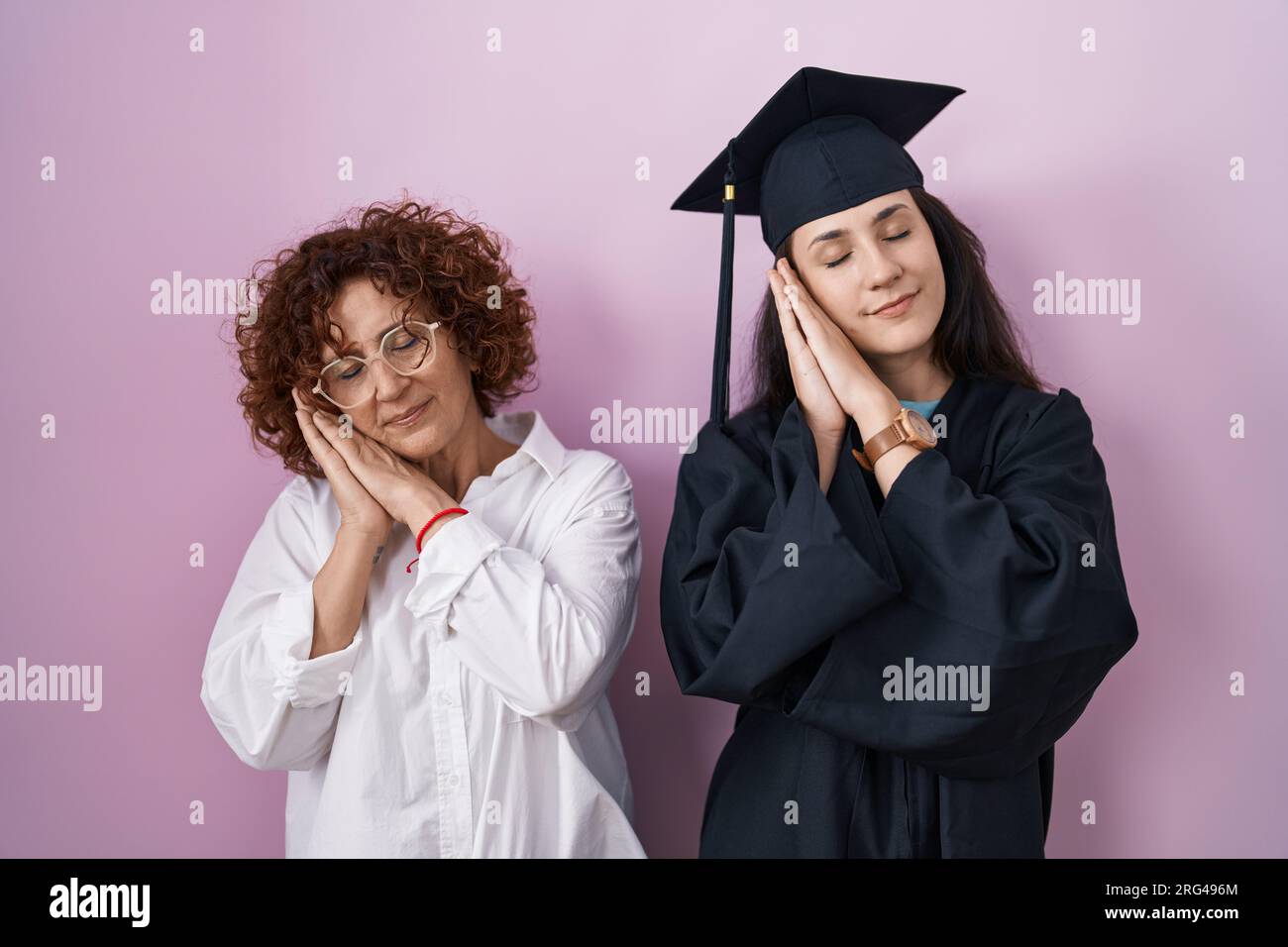 Hispanic mother and daughter wearing graduation cap and ceremony robe ...