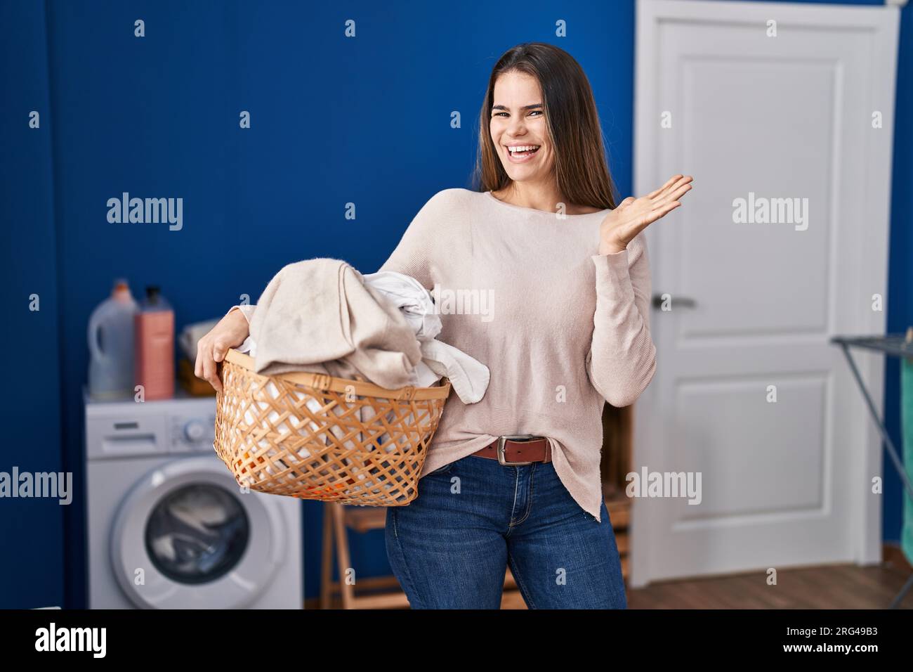 Beautiful woman holding laundry basket celebrating victory with happy ...
