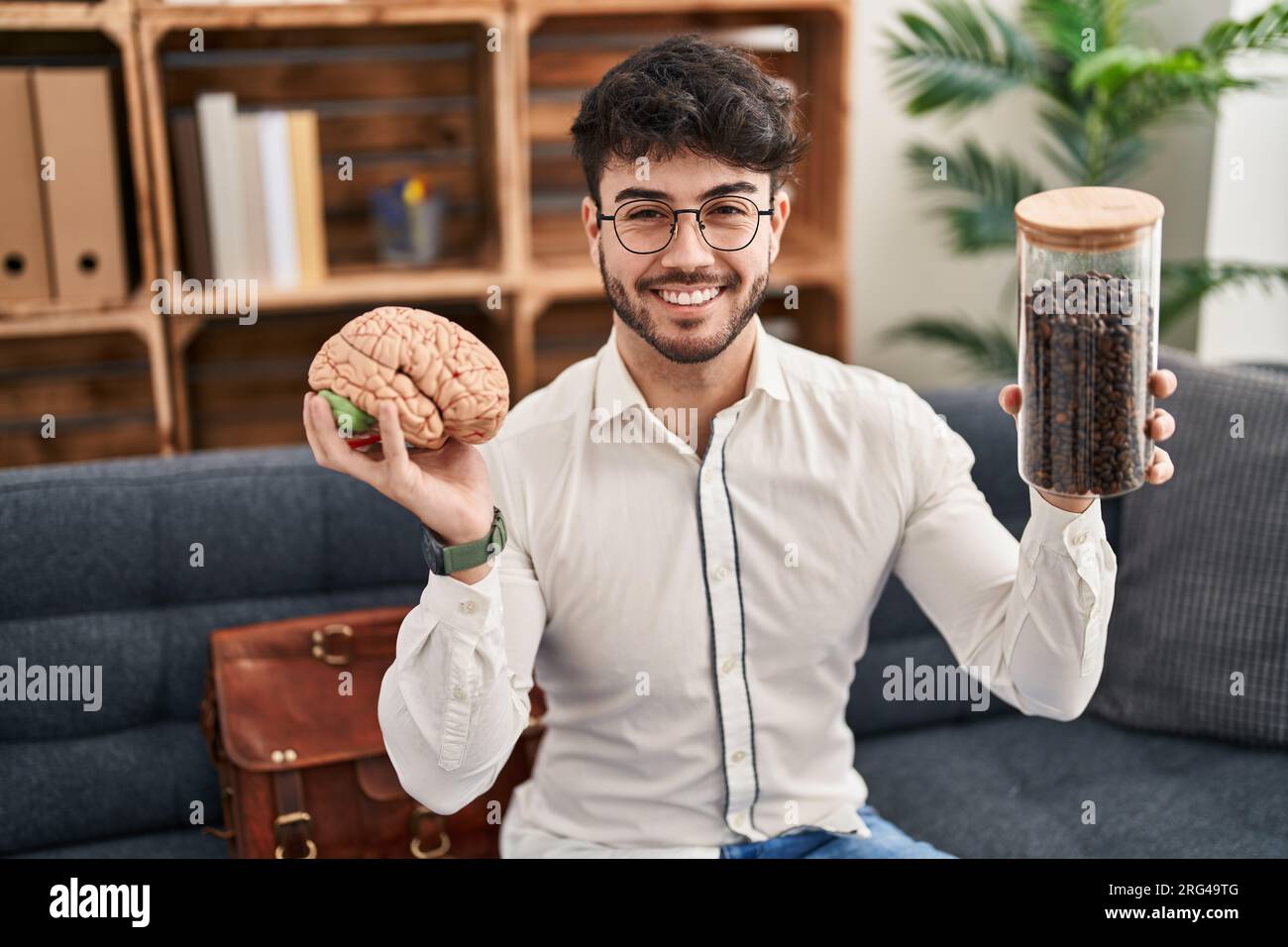 Hispanic man with beard working at therapy office holding brain and ...