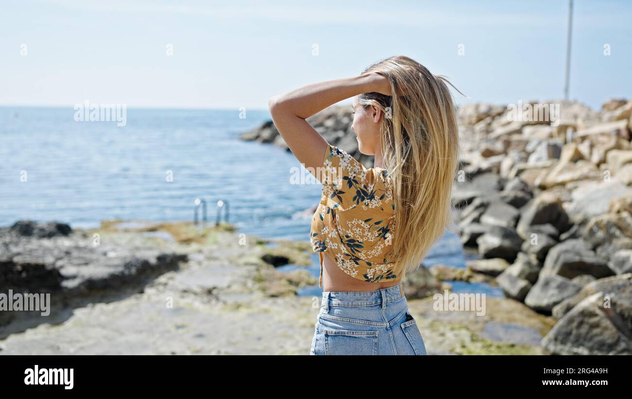 Young blonde woman combing hair backwards at seaside Stock Photo - Alamy