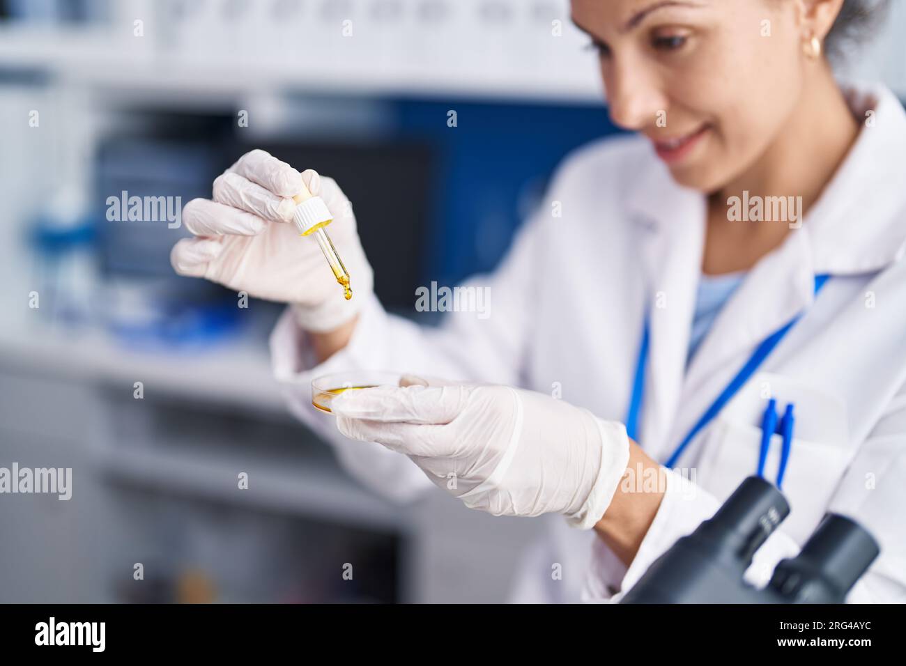 Young woman scientist pouring liquid on sample at laboratory Stock ...