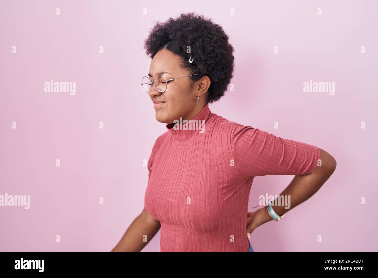 Beautiful african woman with curly hair standing over pink background ...