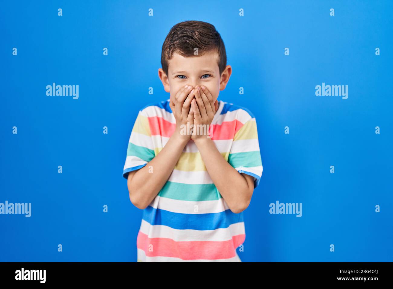 Young caucasian kid standing over blue background laughing and ...
