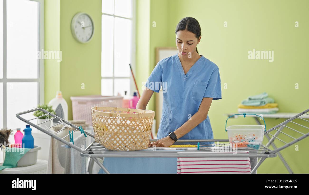 African american woman professional cleaner hanging clothes on ...