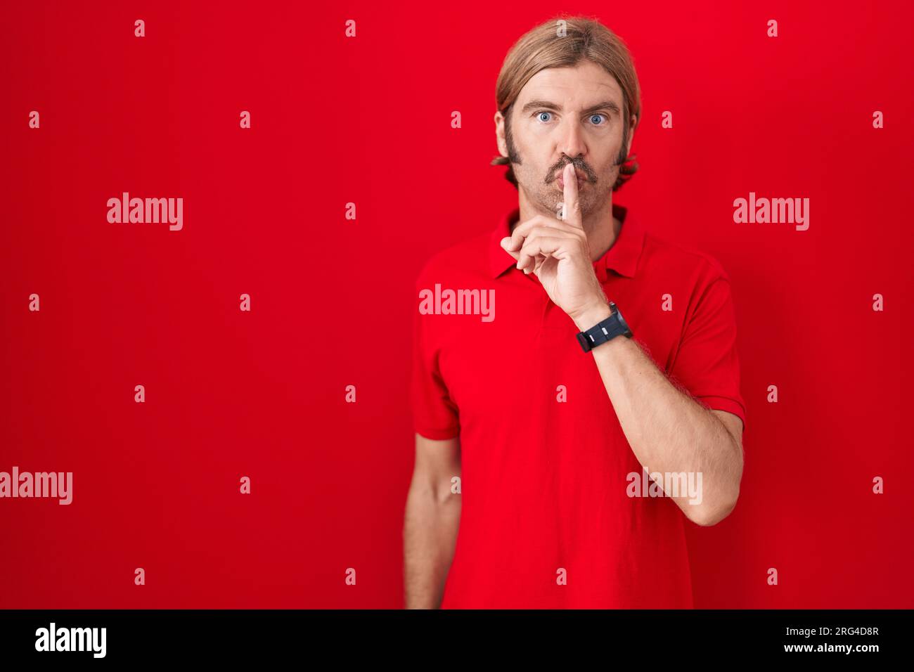 Caucasian man with mustache standing over red background asking to be ...