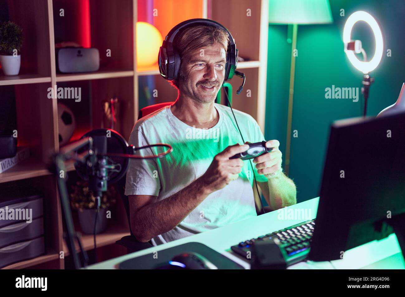 Young blond man streamer playing video game using joystick at gaming ...