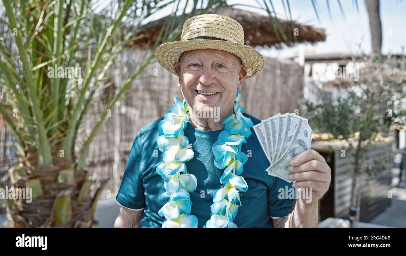 Senior grey-haired man tourist wearing summer hat and hawaiian lei ...