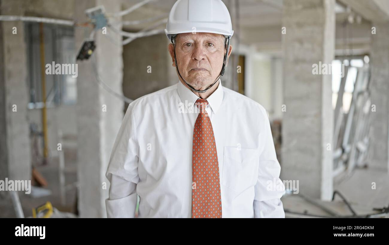 Senior grey-haired man architect standing with relaxed expression at ...