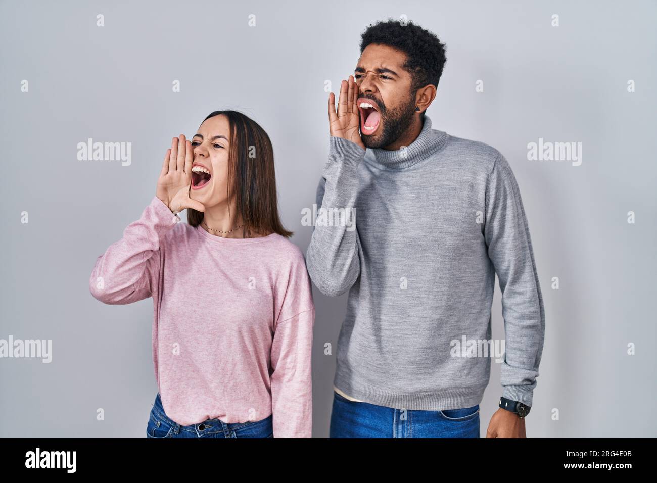 Young hispanic couple standing together shouting and screaming loud to ...