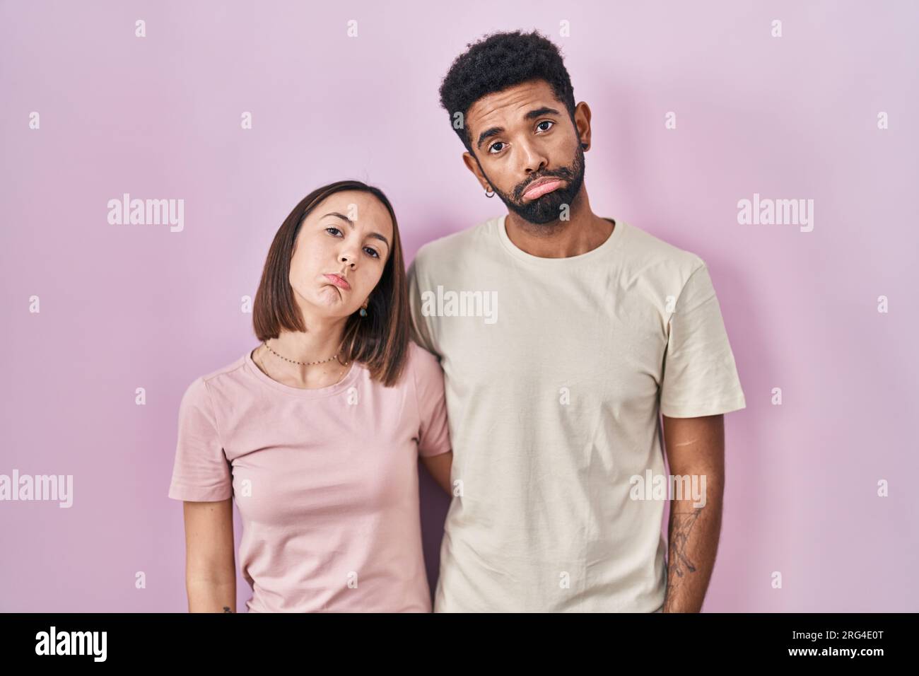 Young hispanic couple together over pink background depressed and worry ...