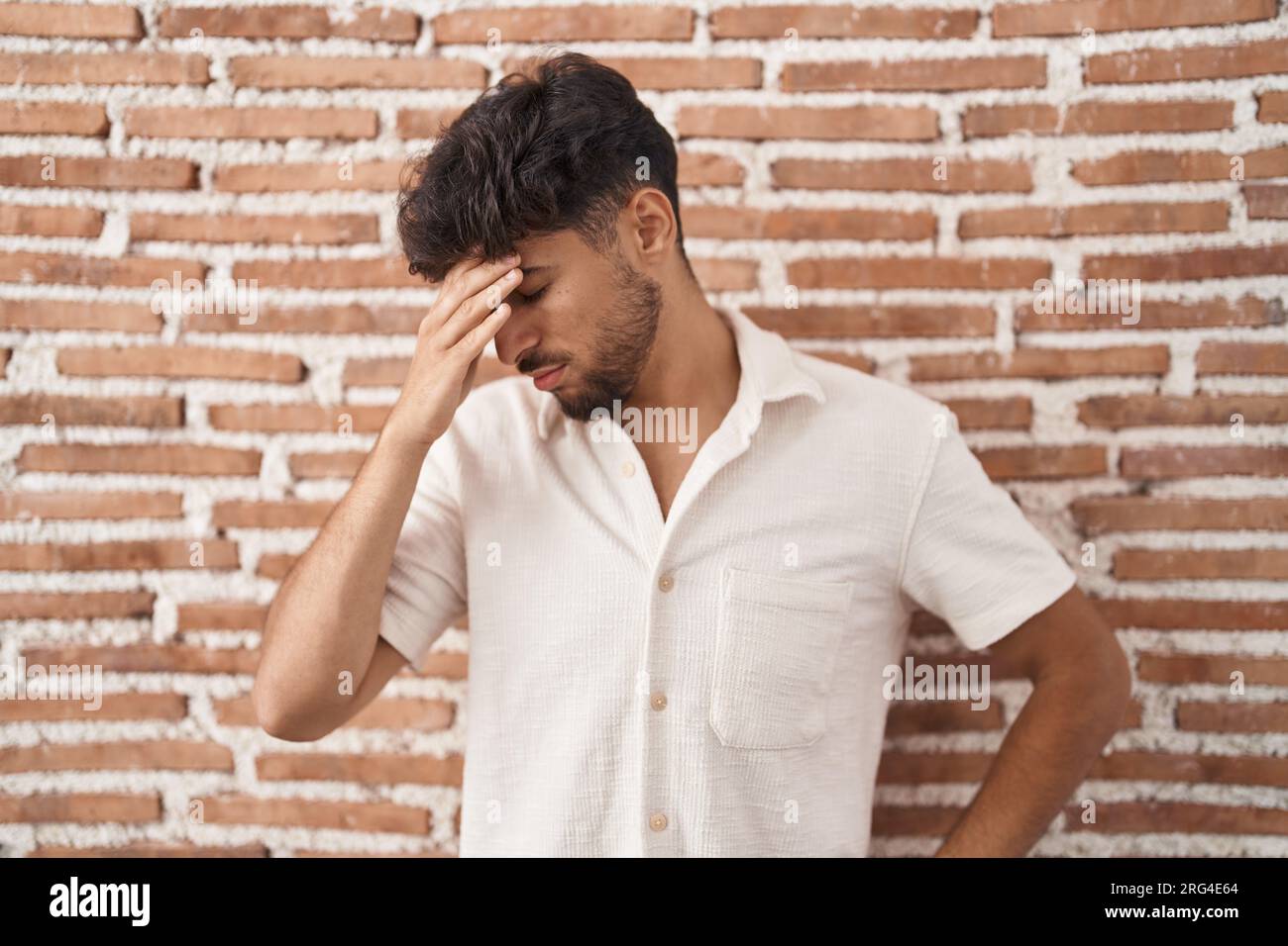 Arab man with beard standing over bricks wall background with sad ...