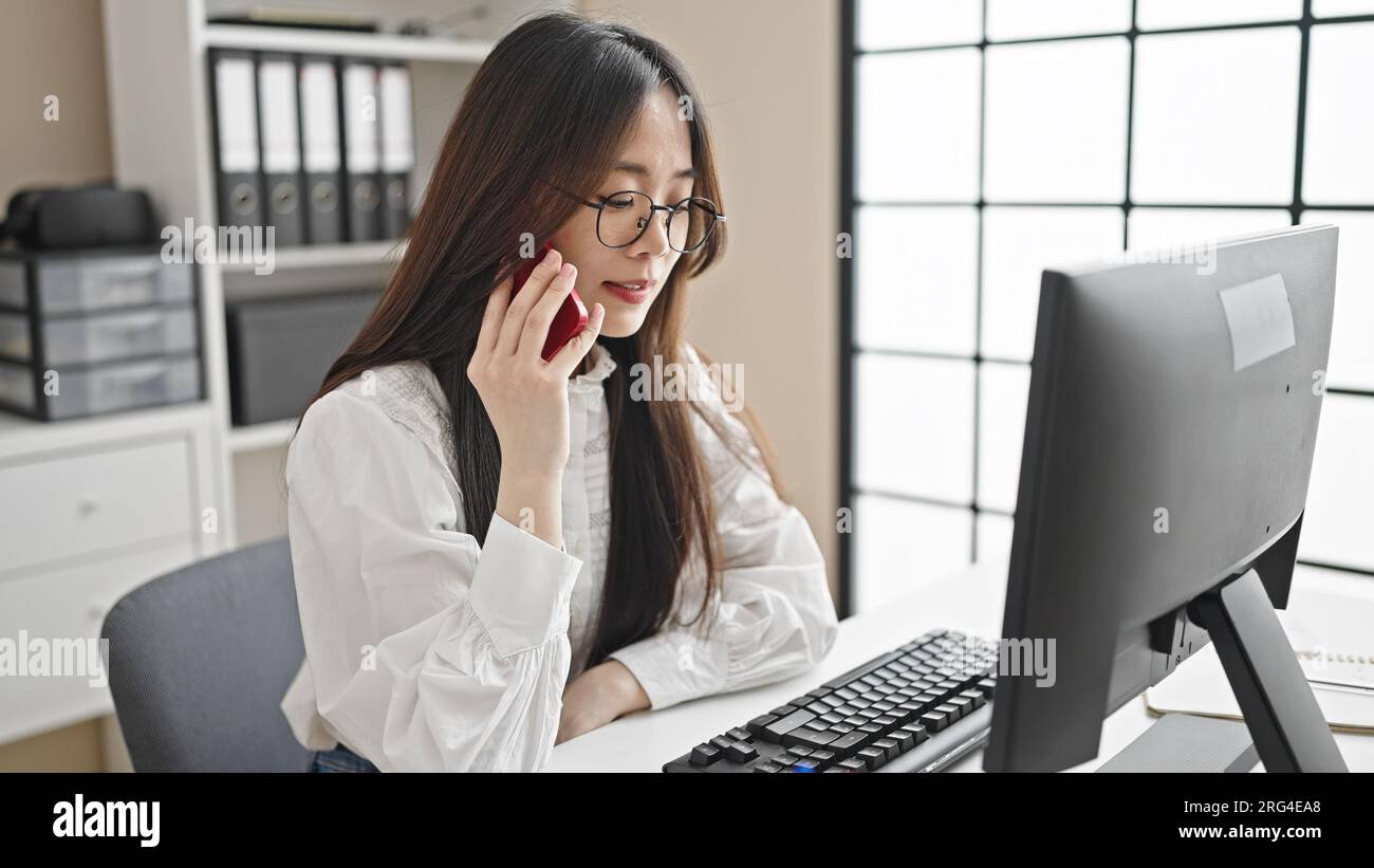 Young chinese woman business worker using computer talking on ...