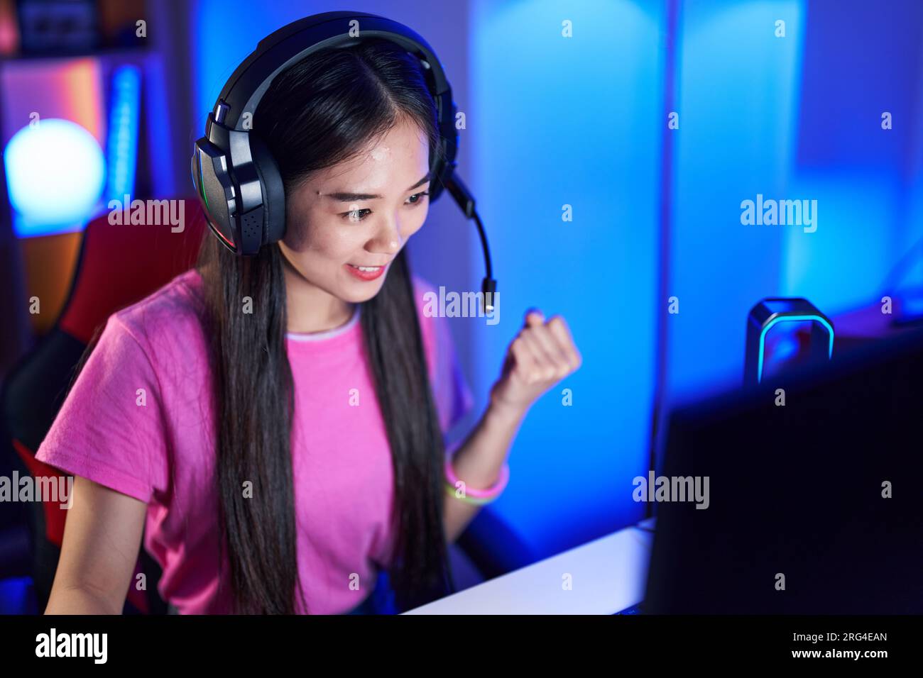 Young chinese woman streamer playing video game with winner expression ...