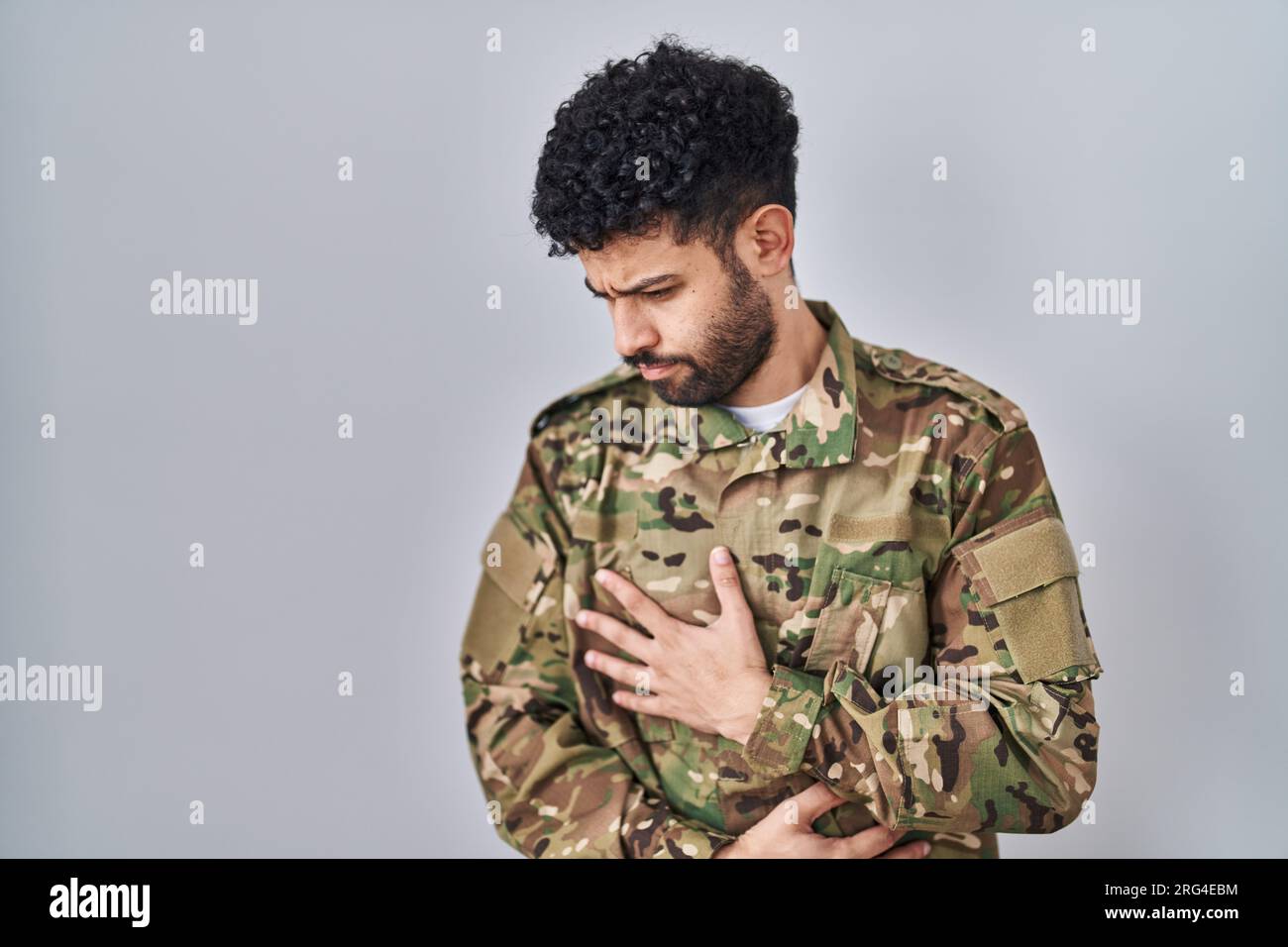 Arab man wearing camouflage army uniform with hand on stomach because ...