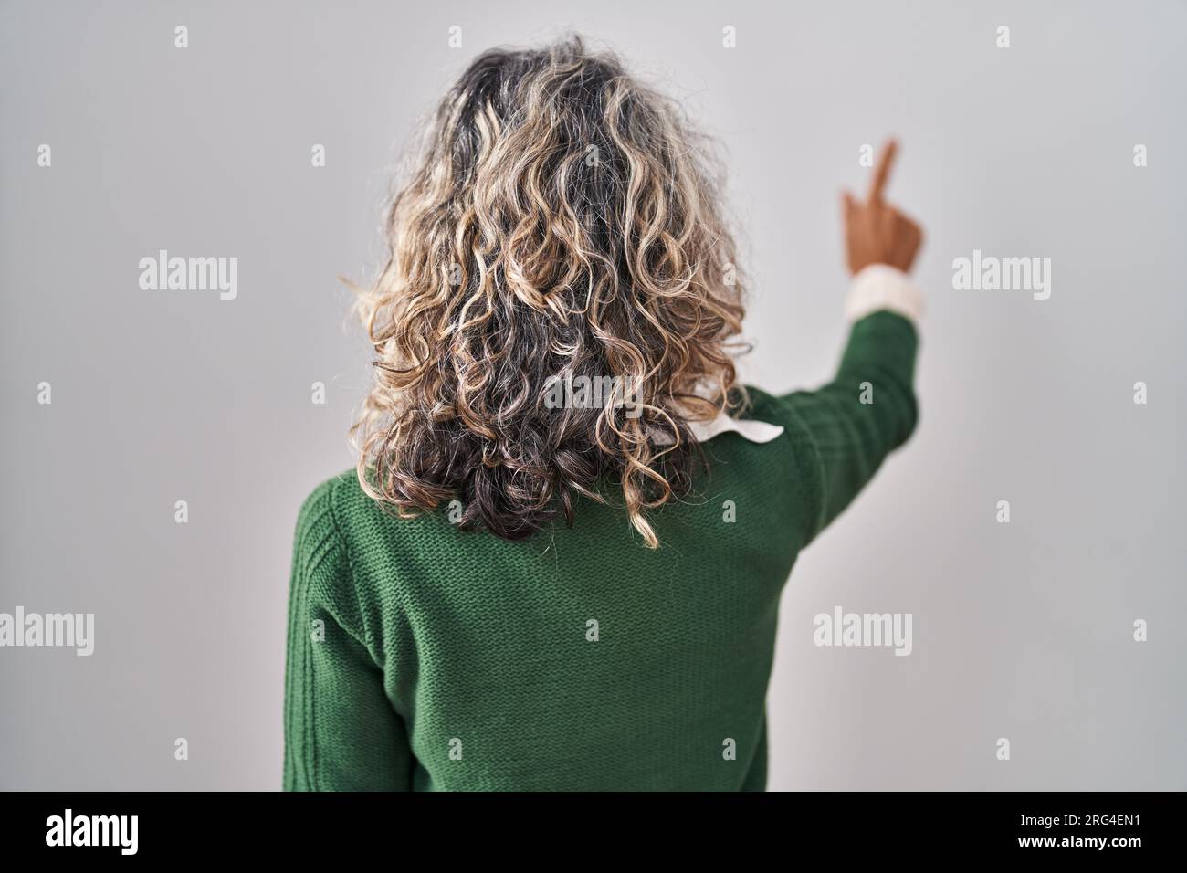 Middle age woman standing over white background posing backwards ...