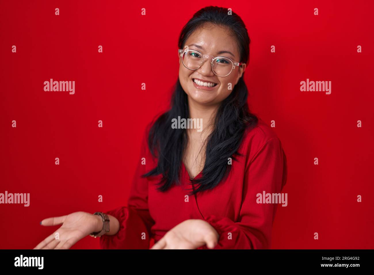 Asian young woman standing over red background smiling cheerful with ...