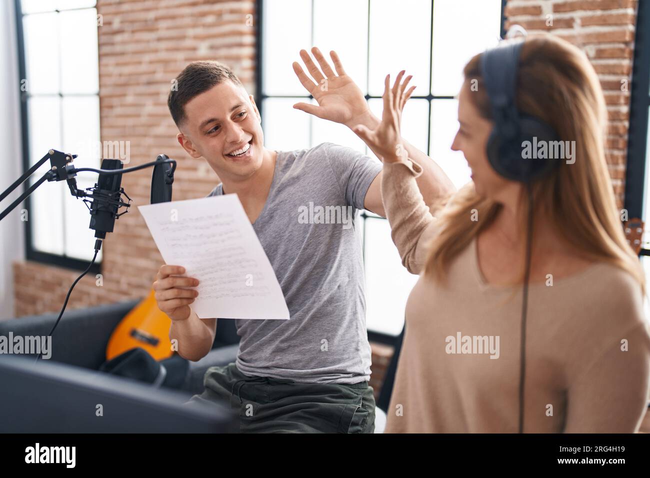 Man and woman musicians singing song high five with hands raised up at ...