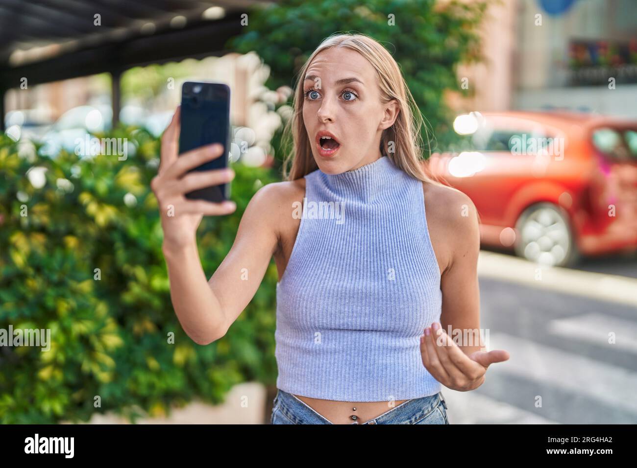 Young caucasian woman doing video call with smartphone scared and ...