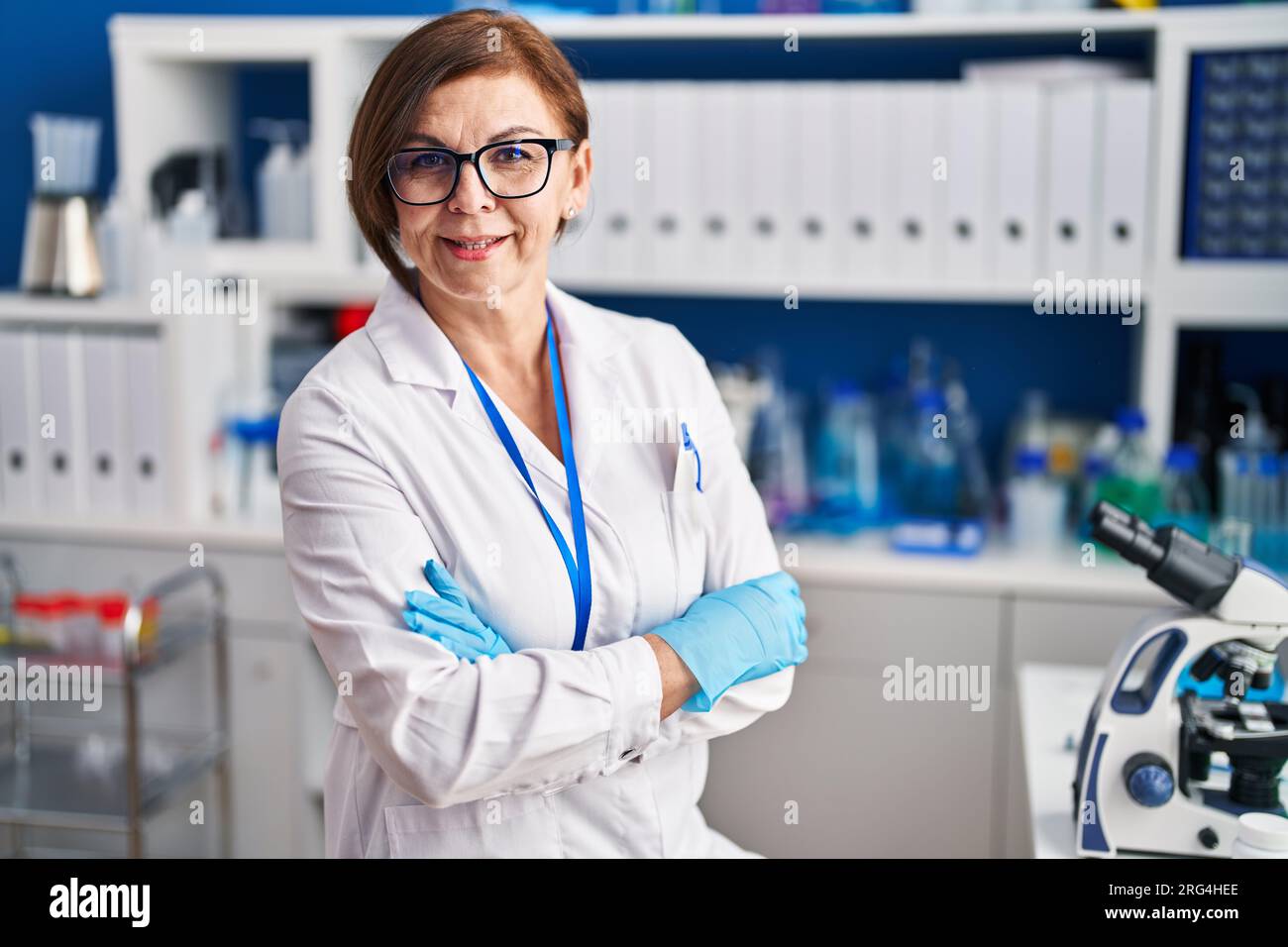 Middle age woman scientist smiling confident sitting with arms crossed ...