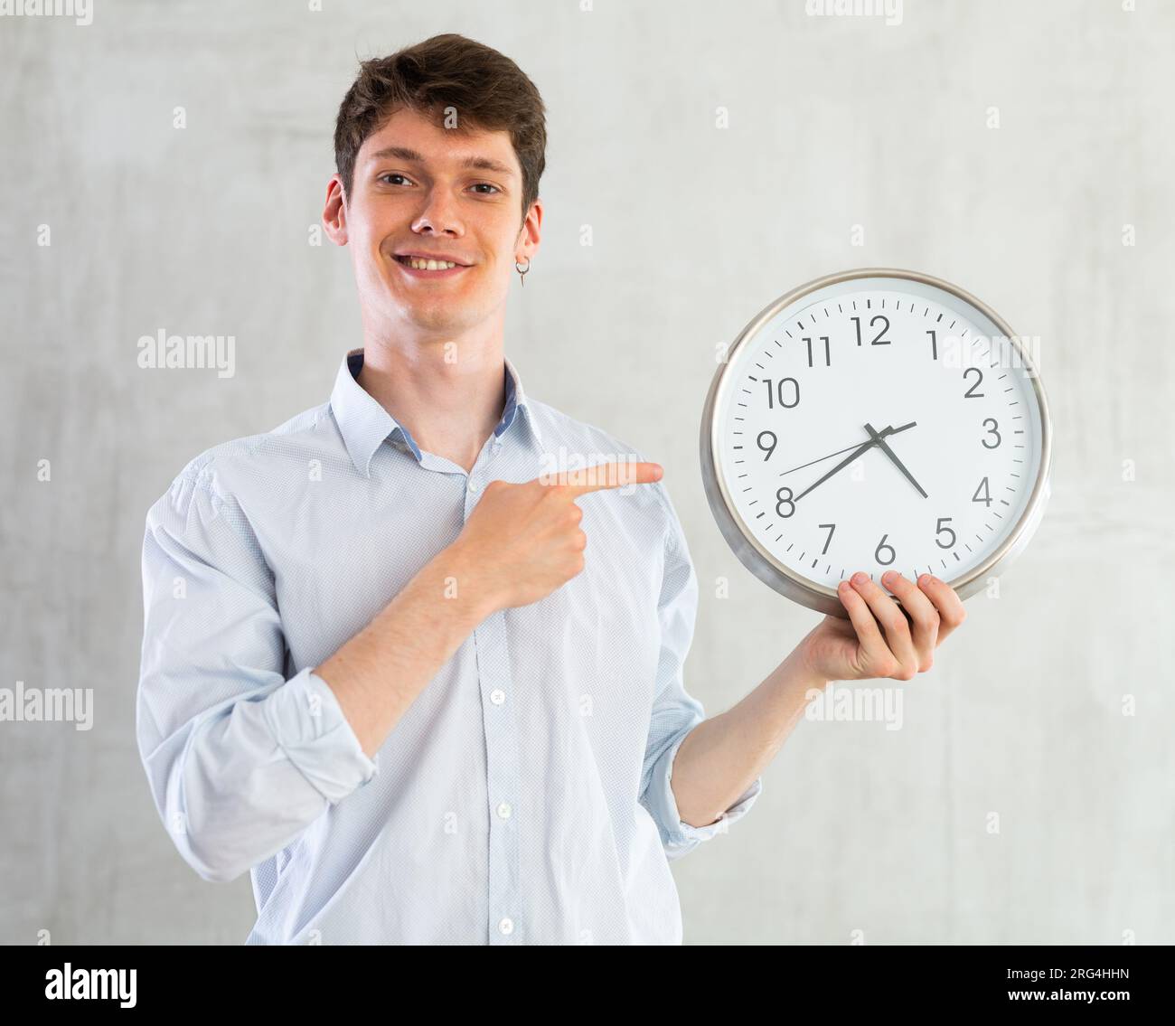 Young guy posing with clock in studio Stock Photo - Alamy