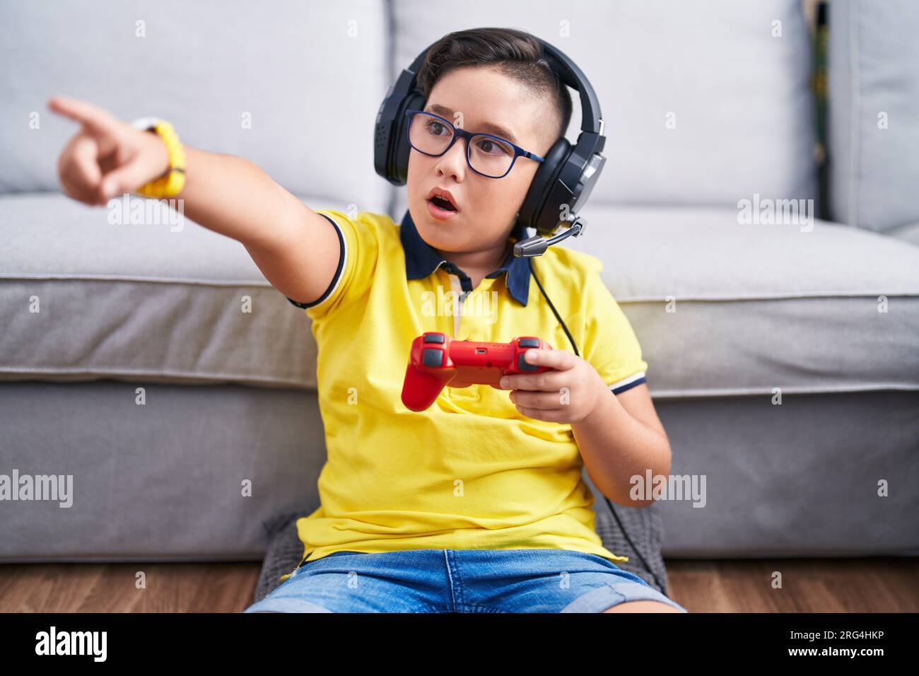 Young hispanic kid playing video game holding controller wearing ...