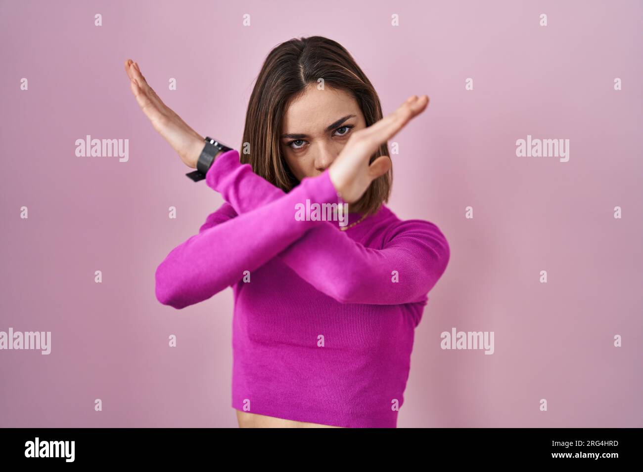 Hispanic woman standing over pink background rejection expression ...