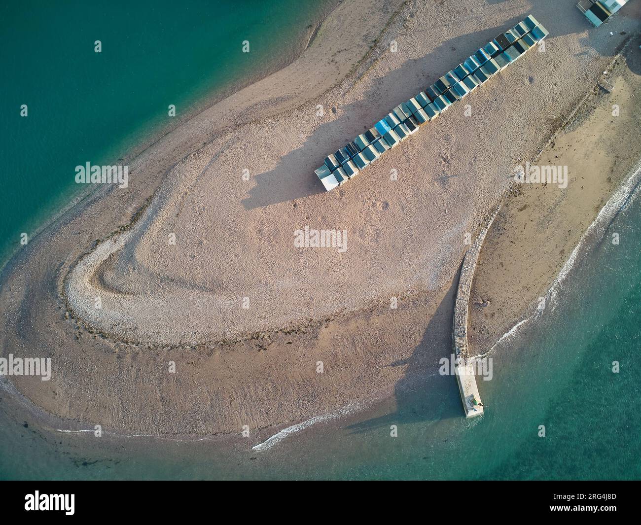 A river mouth sandbar, with beach huts on the sand, boats moored in the ...