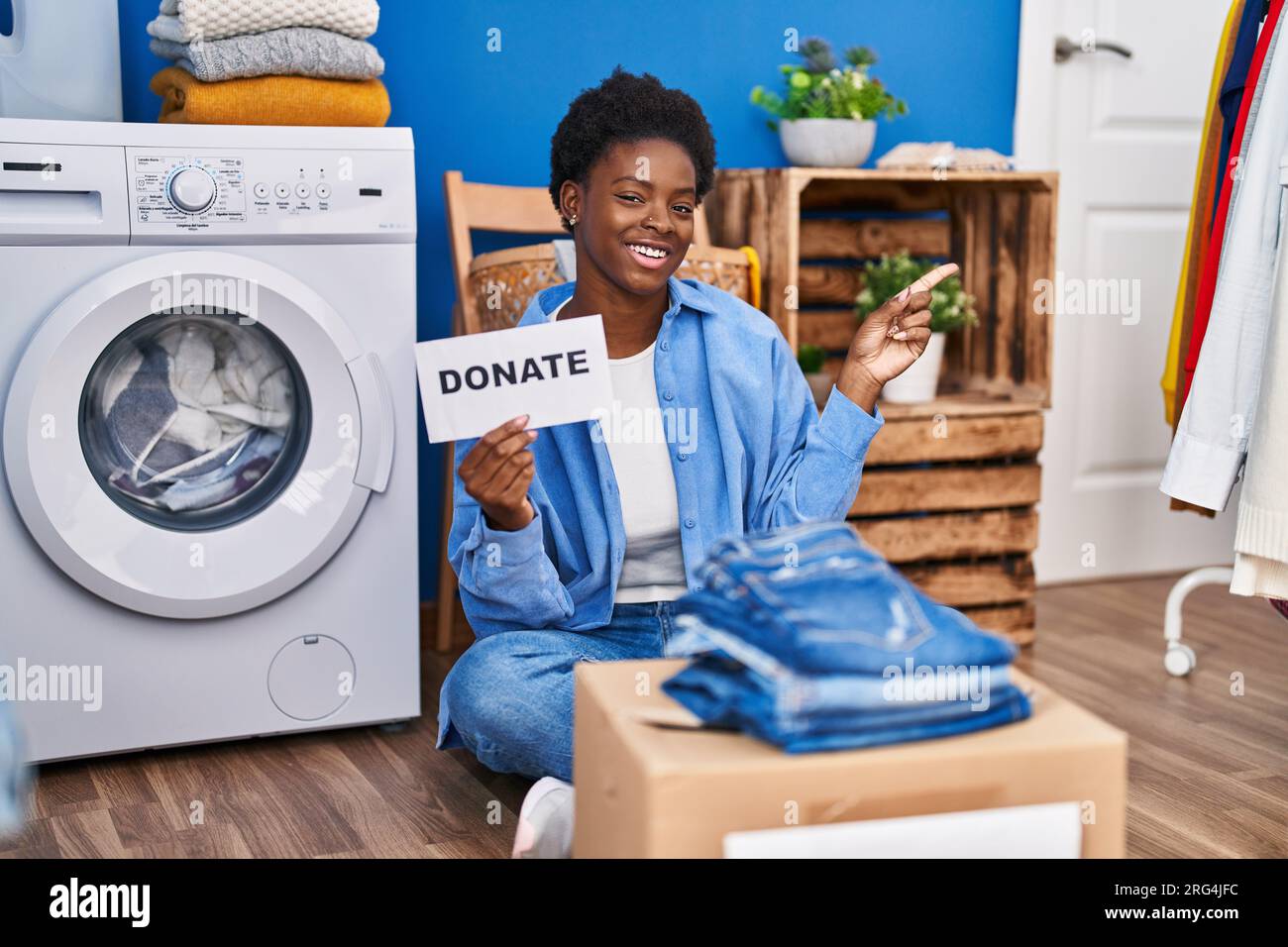 African american woman donating clothes smiling happy pointing with ...
