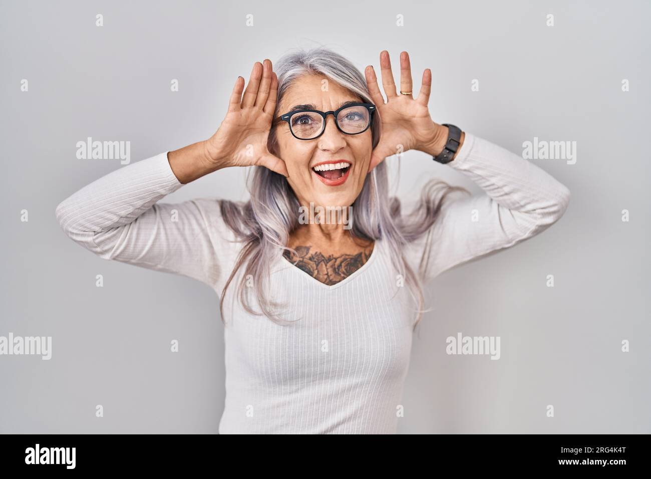 Middle age woman with grey hair standing over white background smiling ...