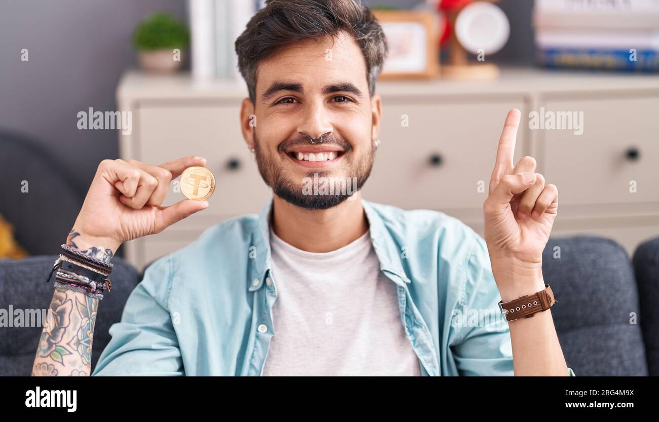 Young hispanic man with tattoos holding tether cryptocurrency coin ...