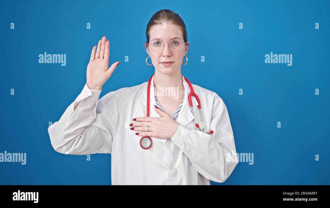 Young blonde woman doctor making an oath with hand on chest over ...
