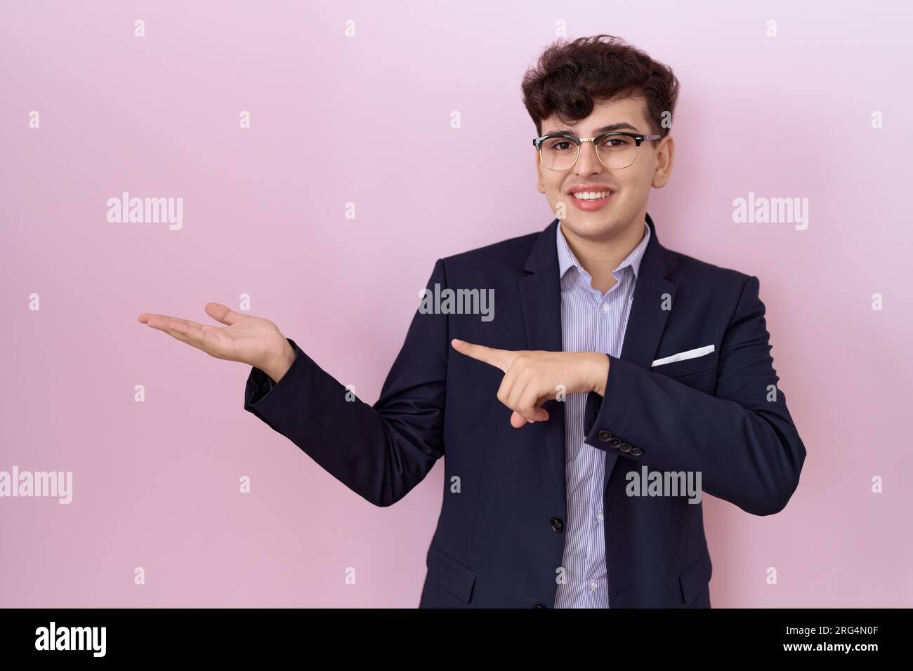 Young non binary man with beard wearing suit and tie amazed and smiling ...