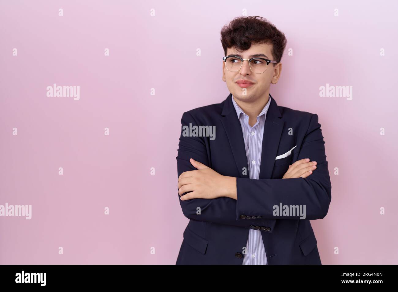 Young non binary man with beard wearing suit and tie smiling looking to ...